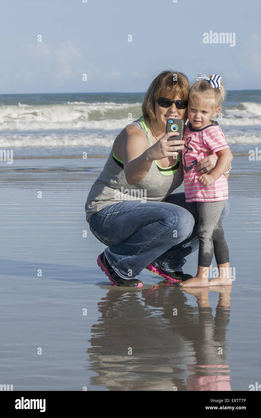 Young Mother With Her Daughter Taking A Selfie With The Ocean In The
