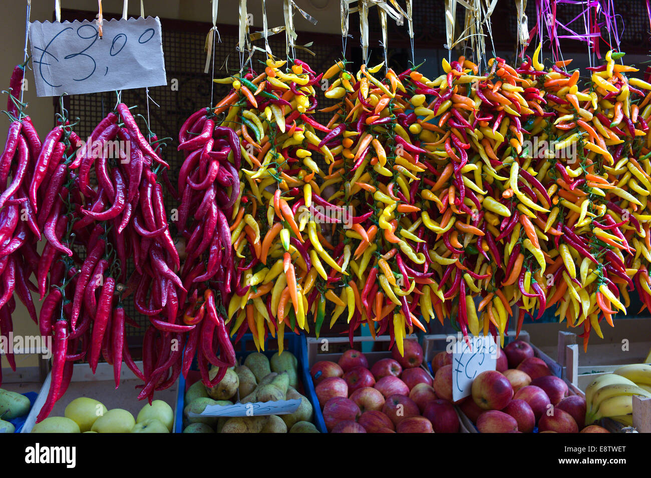 A display of strings of colourful chilli peppers hanging on a street ...