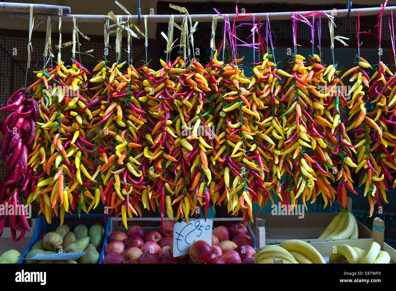 A display of strings of colourful chilli peppers hanging on a street ...
