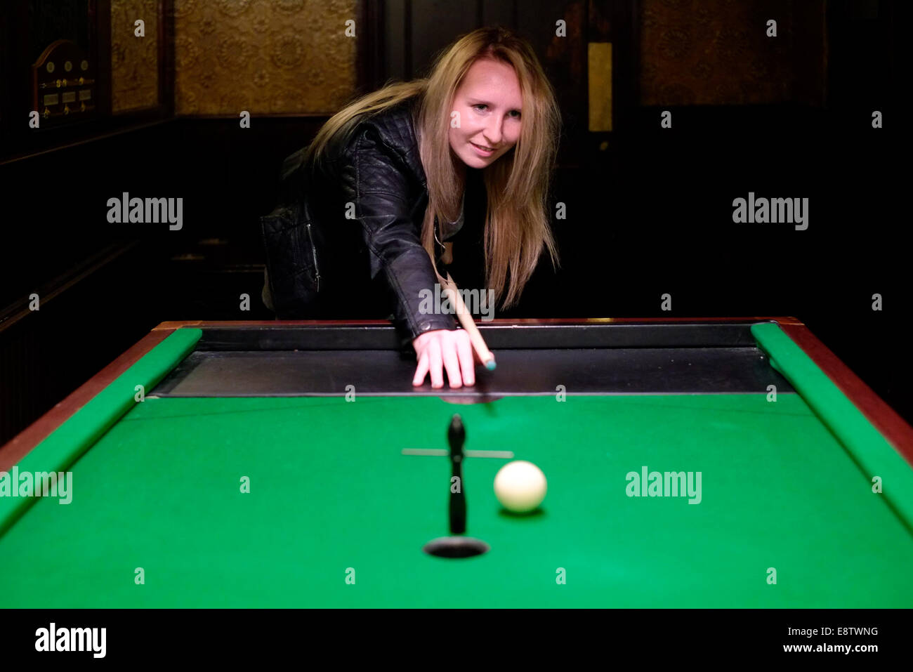 young woman playing a game of bar billiards in a traditional british ...