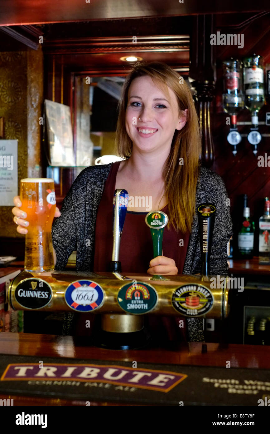smiling young barmaid serving a pint in a traditional british pub the ...