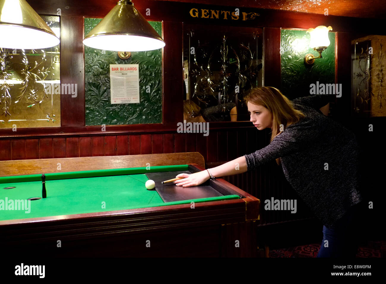 young woman playing bar billiards in a traditional british pub the ...