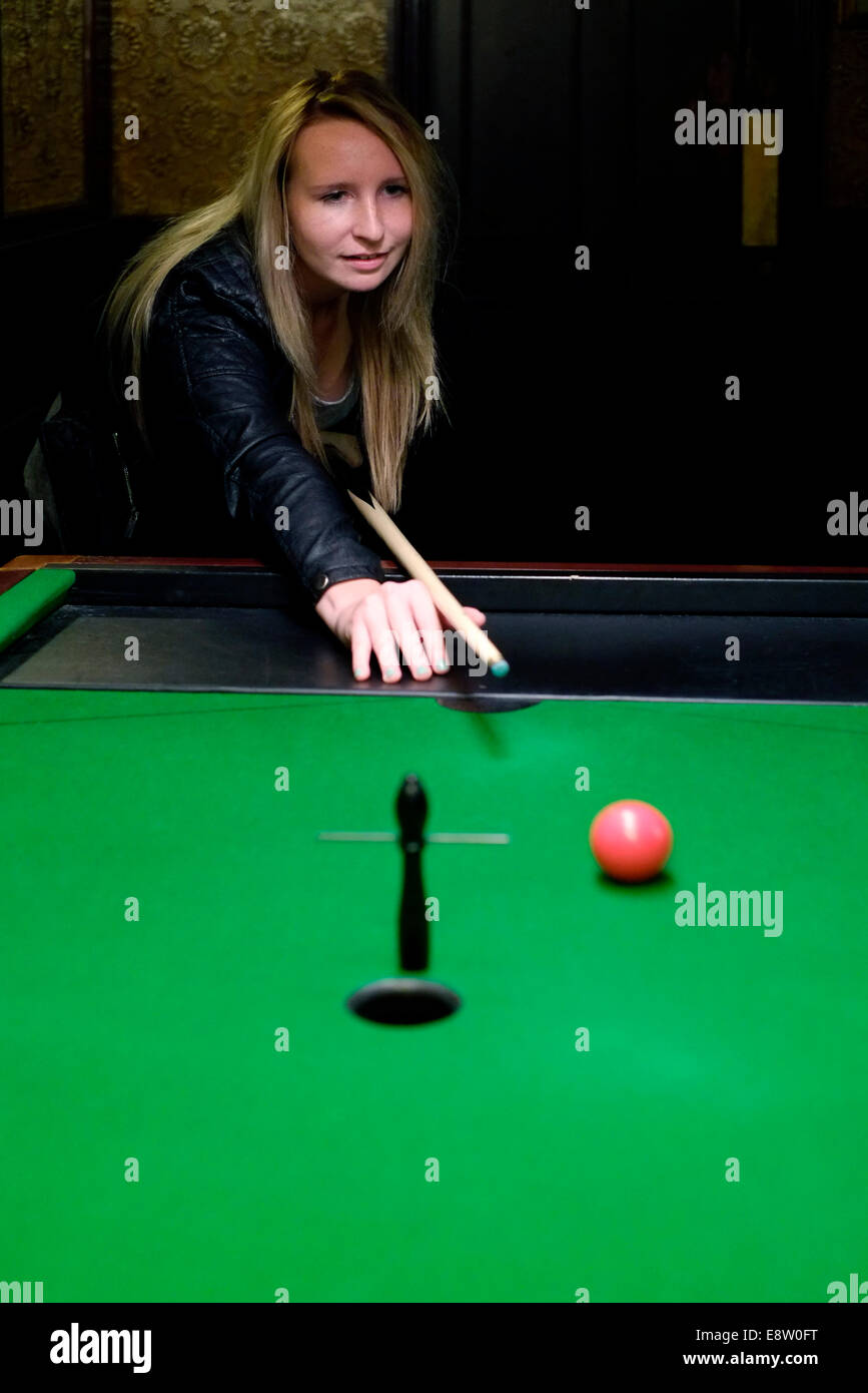 young woman playing a bar billiards in a traditional british pub the ...