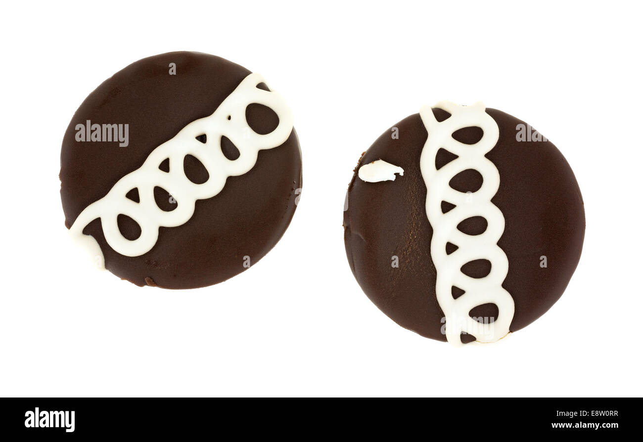 Two small chocolate iced bite sized cakes with vanilla icing on a white ...