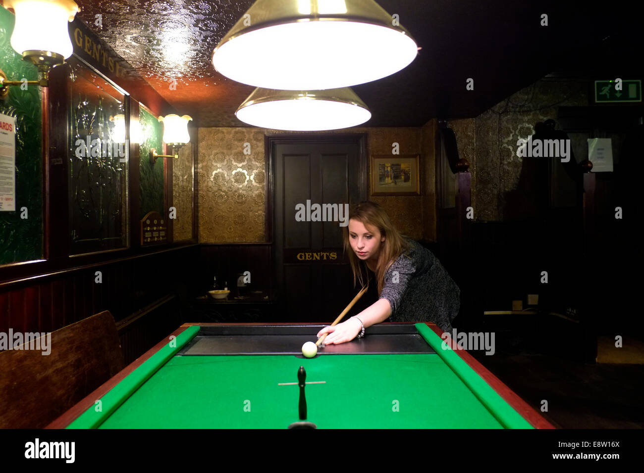 young woman playing bar billiards in a traditional british pub the ...
