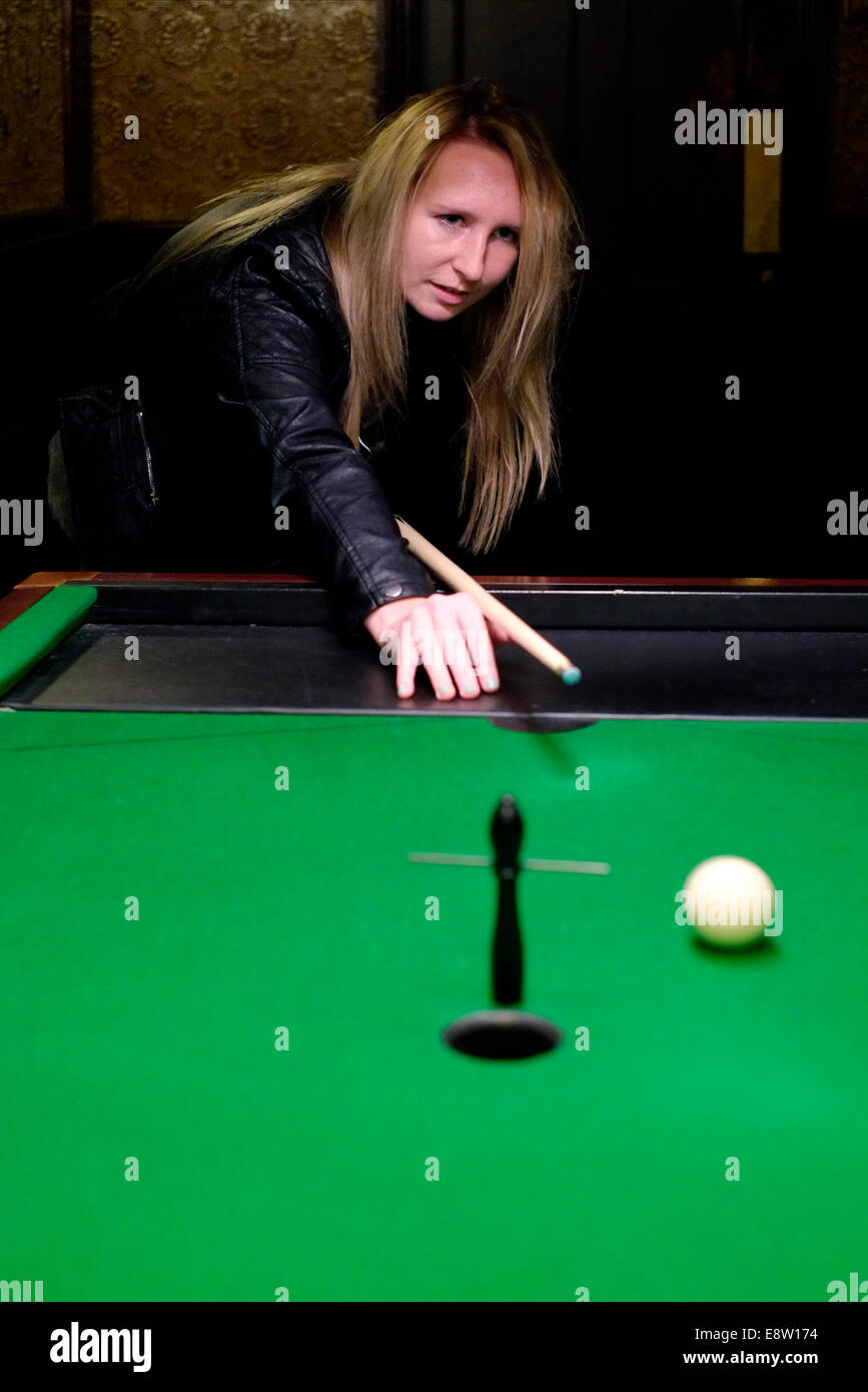 young woman playing bar billiards game in a traditional british pub the ...