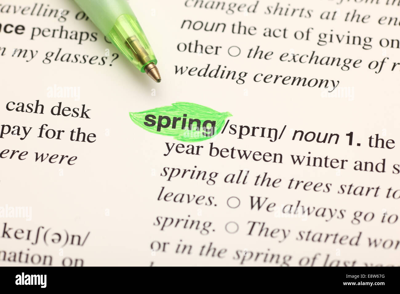 The word "spring" highlighted in green on a dictionary and ballpoint ...