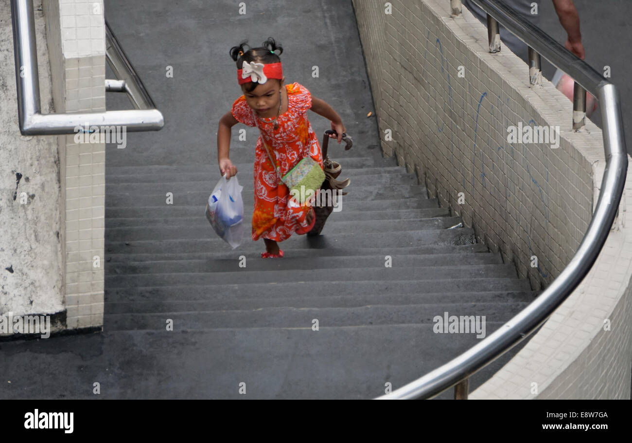 Young girl climbing steps with shopping bag and umbrella,city living ...