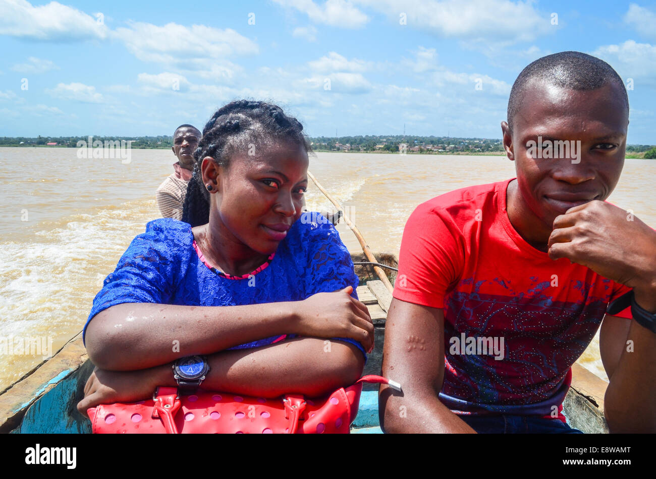 A Nigerian couple on a small wooden boat crossing the Niger river ...
