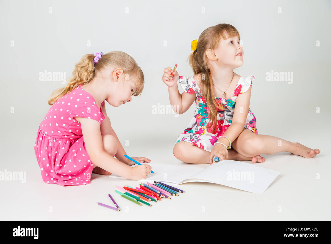 Two lovely girls drawing with colorful pencils Stock Photo - Alamy