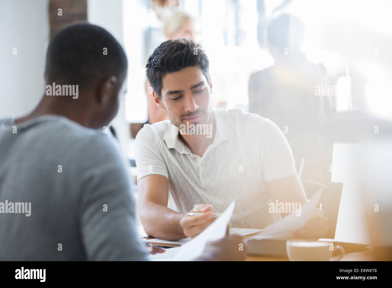 Businessmen looking through documents in cafe together Stock Photo - Alamy