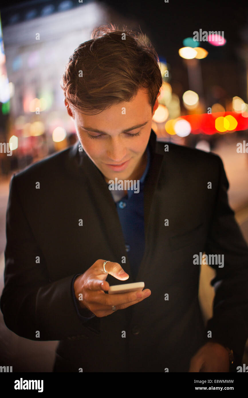 Man using cell phone on city street at night Stock Photo - Alamy