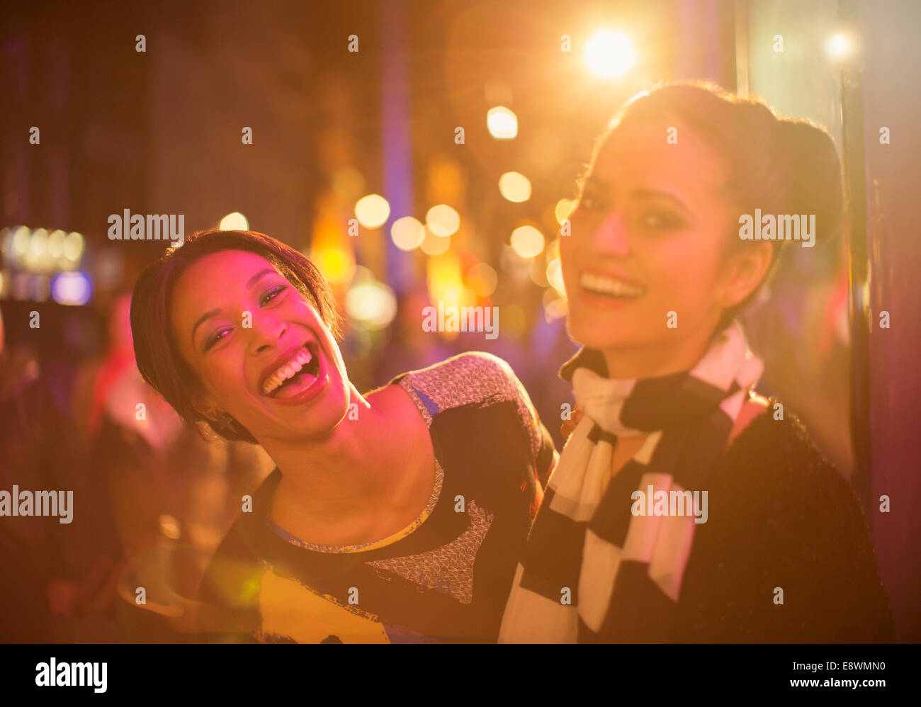 Friends laughing together on city street at night Stock Photo - Alamy