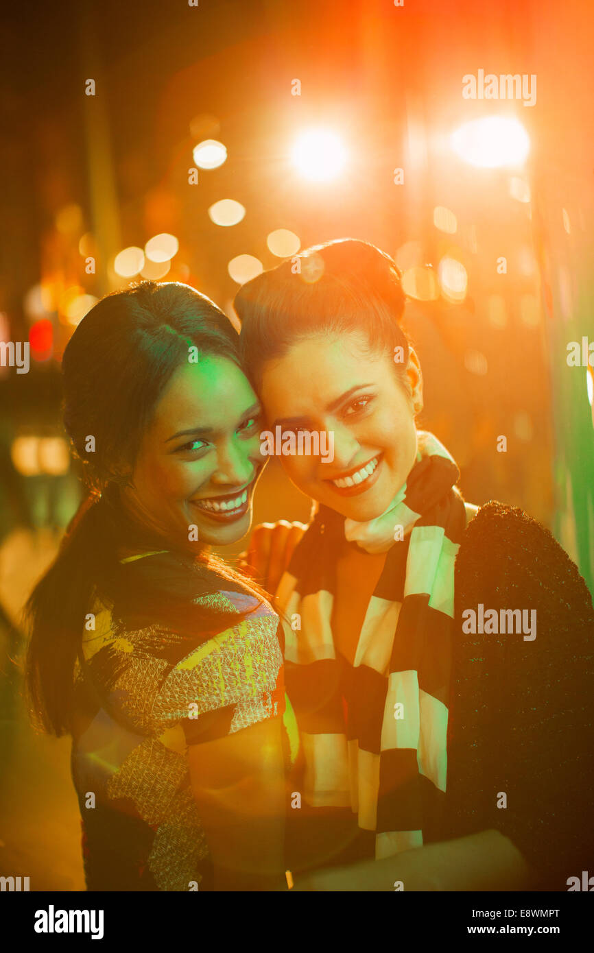 Women smiling together on city street at night Stock Photo - Alamy