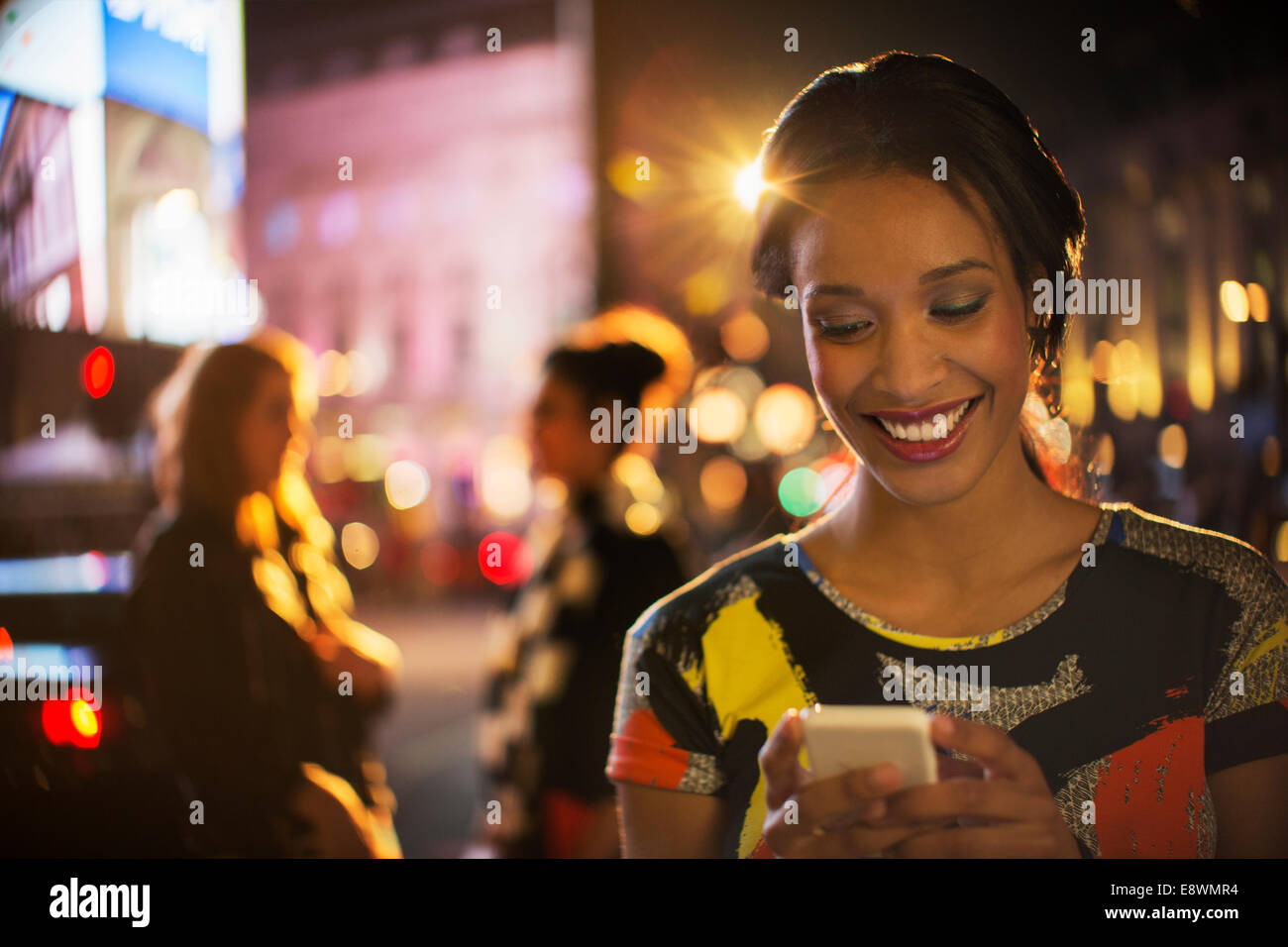 Woman using cell phone on city street at night Stock Photo - Alamy