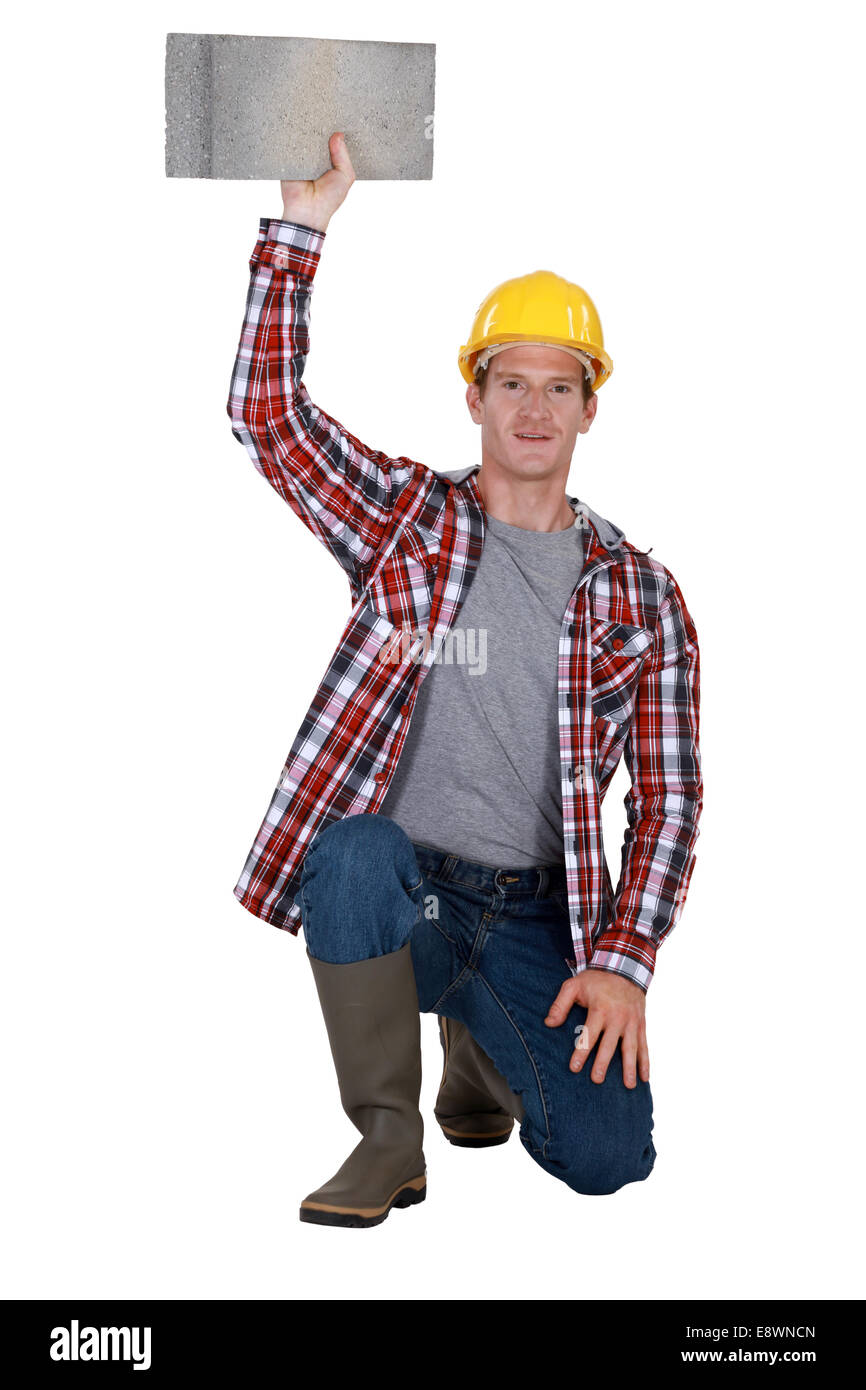 Bricklayer holding block of concrete Stock Photo - Alamy