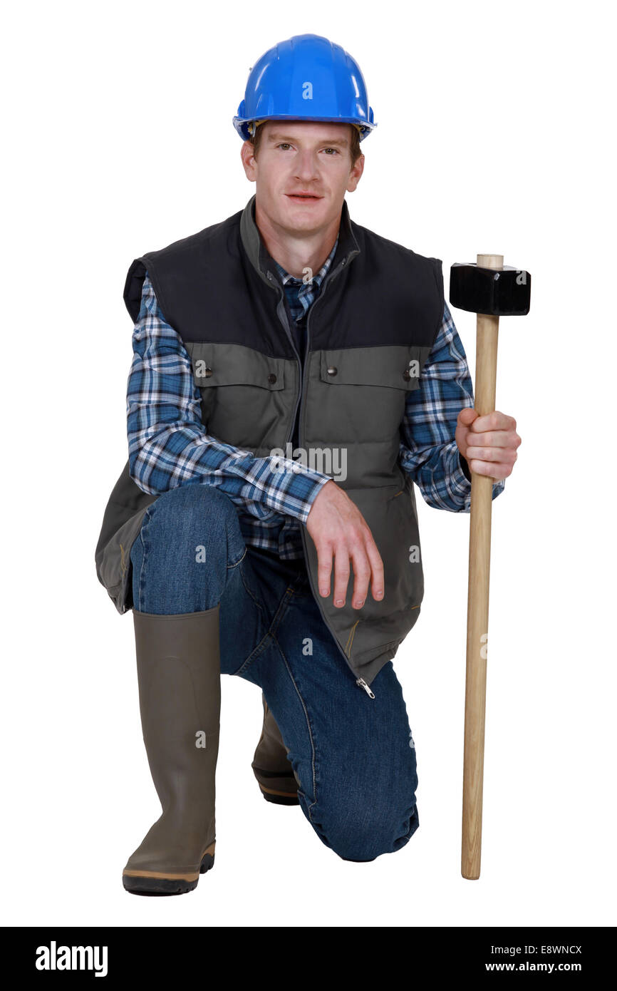 Workman crouching with hammer Stock Photo - Alamy