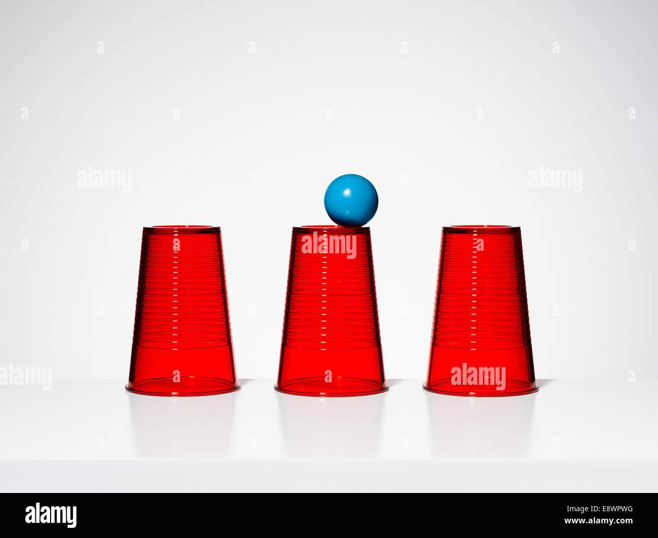 Blue ball balancing on middle of three red cups Stock Photo - Alamy