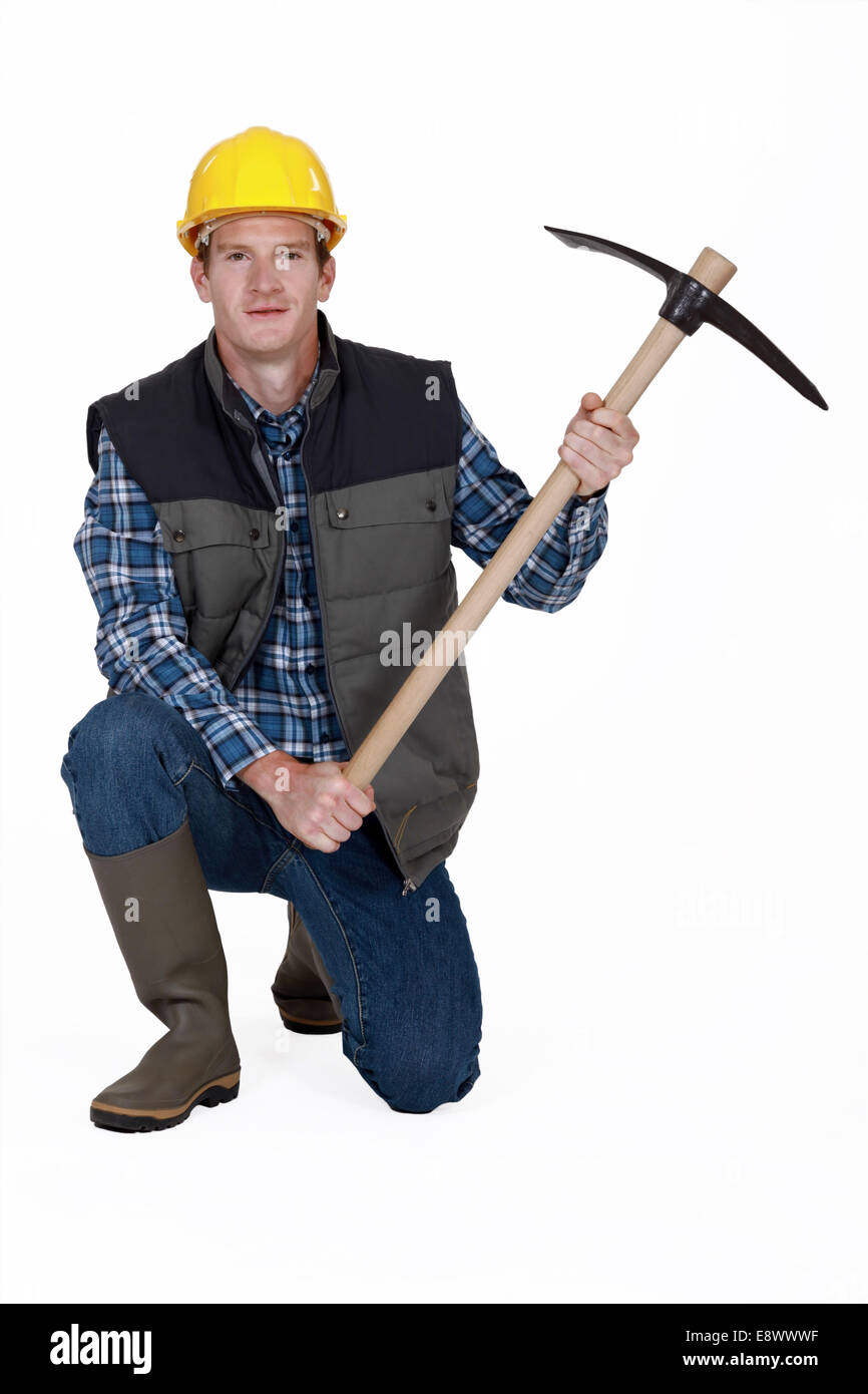 Worker kneeling with pick-ax Stock Photo - Alamy