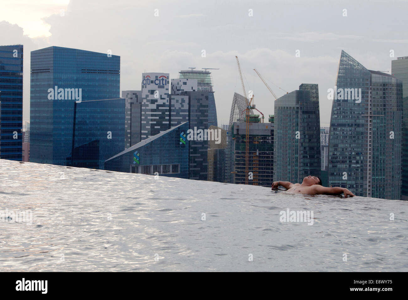 A guest in the rooftop infinity pool and Singapore skyline at Marina ...