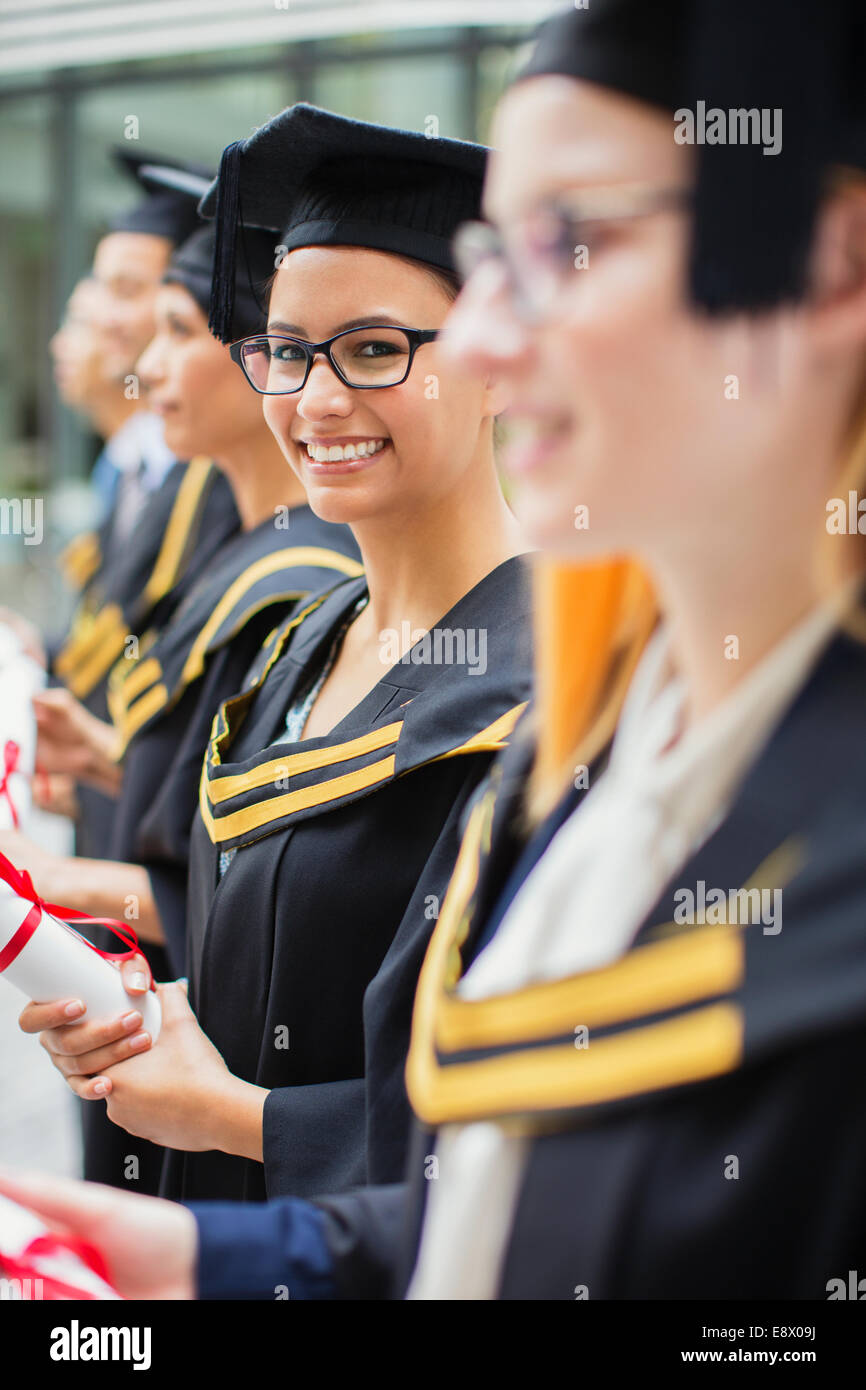 Student in cap and gown standing with colleges Stock Photo - Alamy