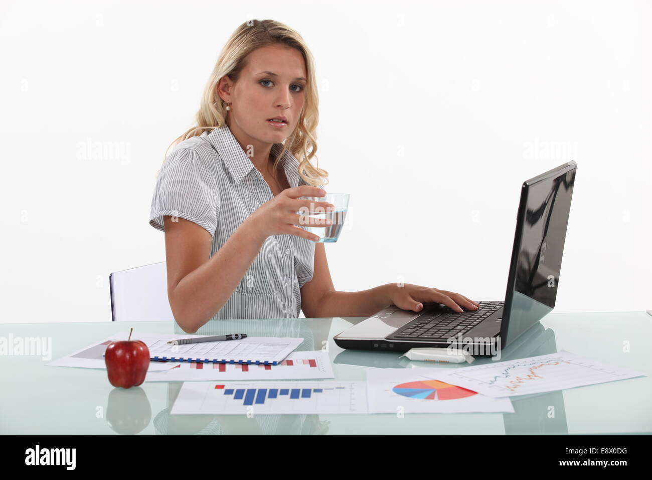 Woman sat at desk drinking Stock Photo - Alamy