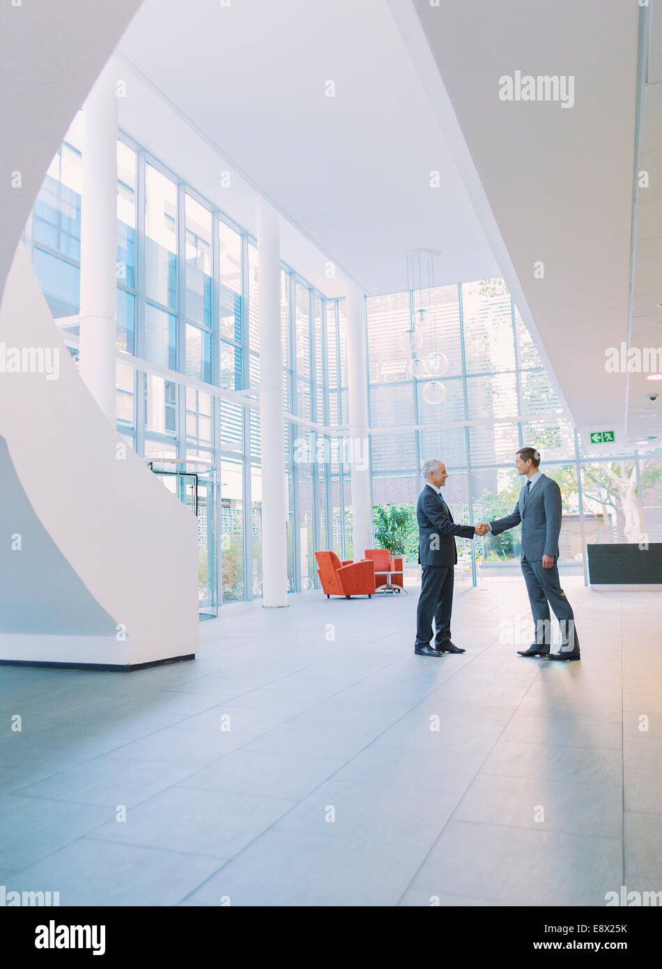 Businessmen shaking hands in office building Stock Photo - Alamy