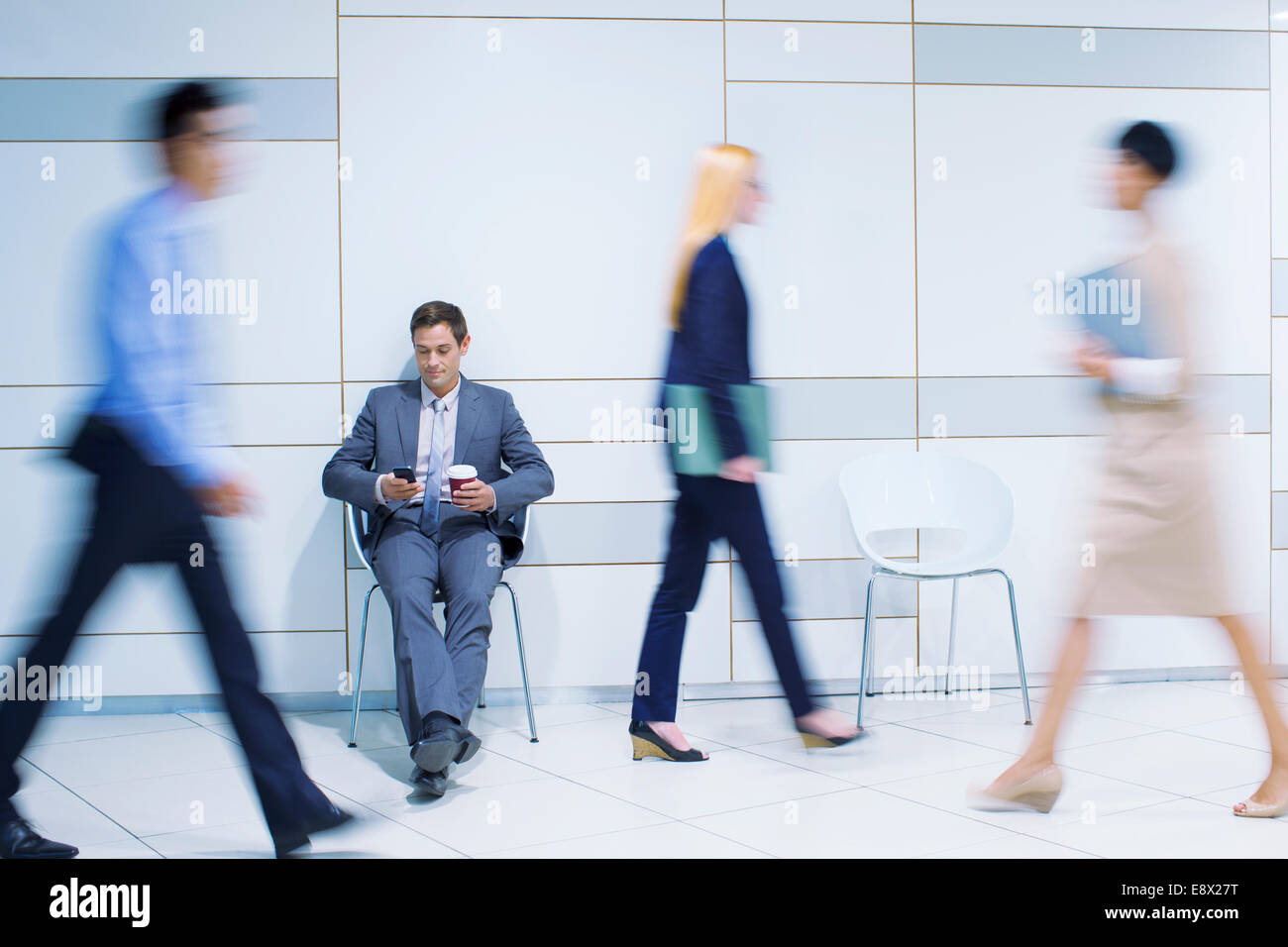 Businessman sitting using cell phone in office building Stock Photo - Alamy