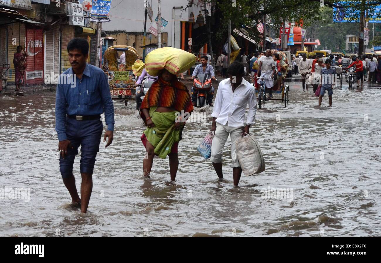 People walk through a road submerged with water after the heavy rain in ...