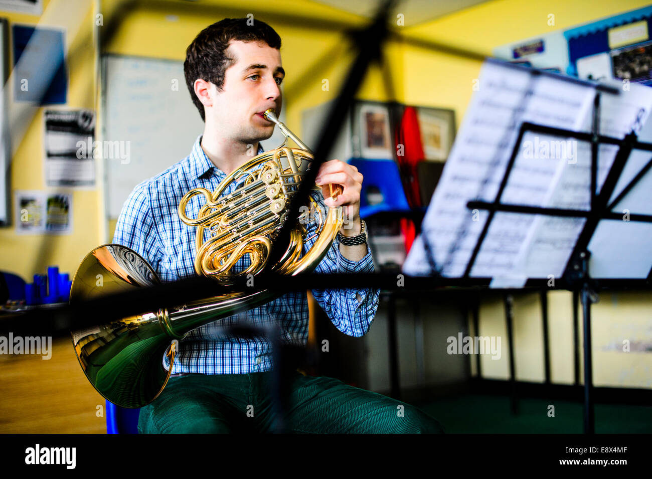 A Young teenage male musician practicing playing french horn, part of ...