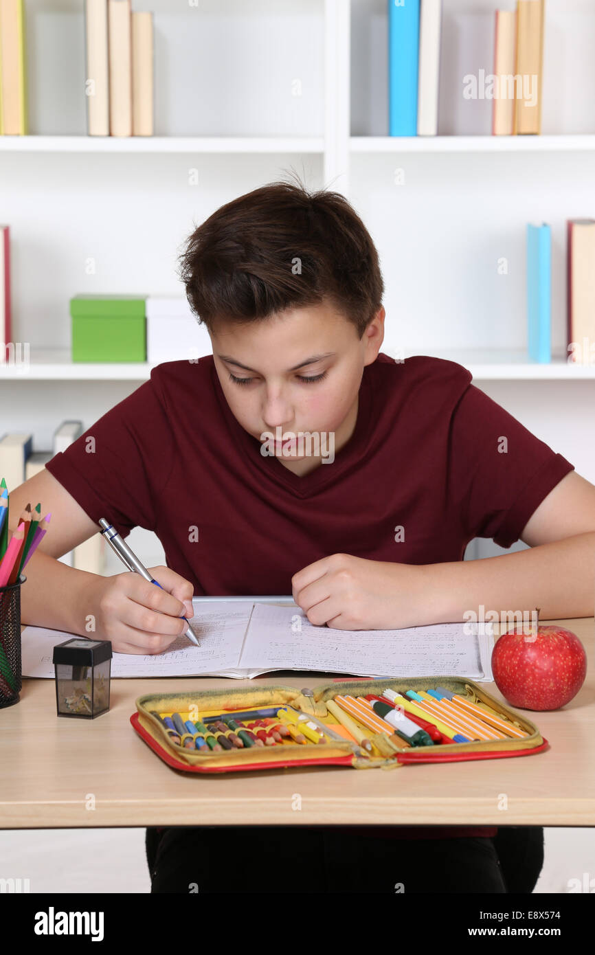 Young student writing in his exercise book at school in a classroom ...