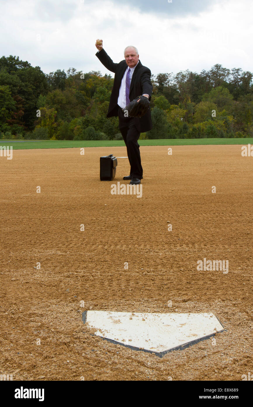 Businessman throwing a pitch on a baseball or softball playing field ...