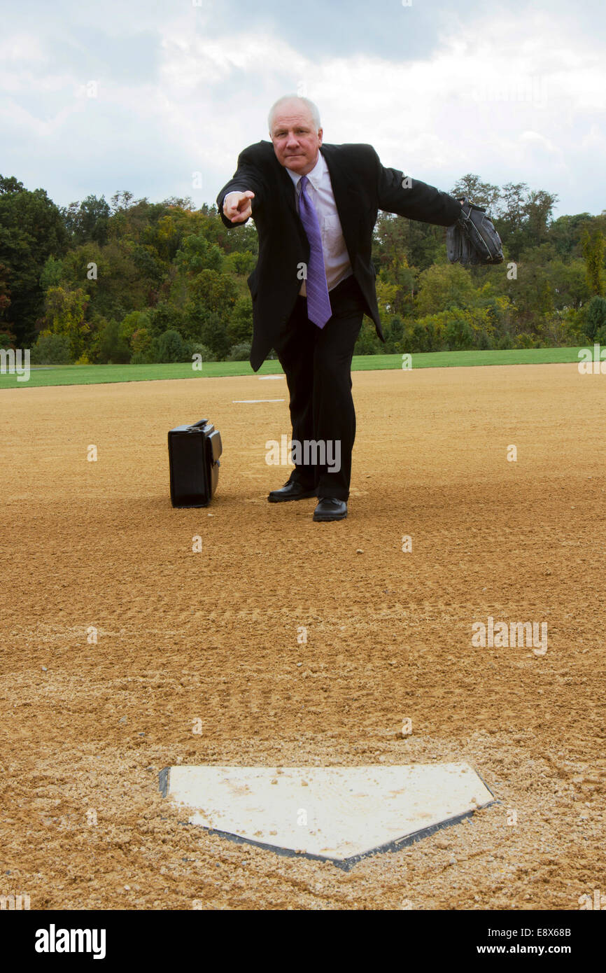 Businessman throwing a pitch on a baseball or softball playing field ...