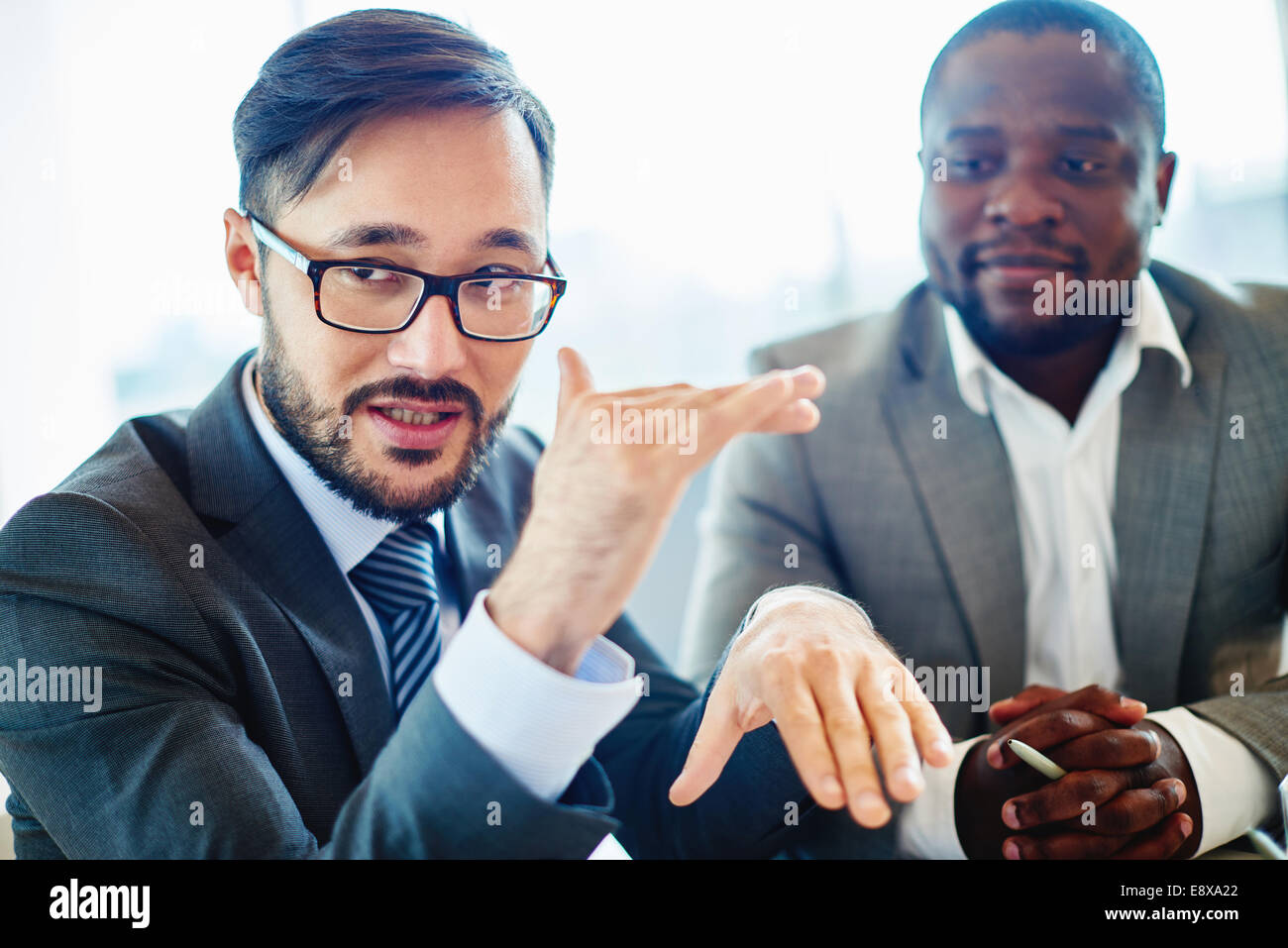 Serious businessman of Asian ethnicity explaining his ideas to ...