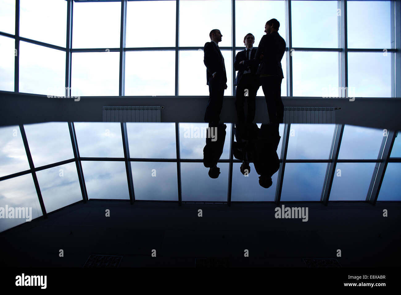 Three business partners having a discussion standing against a ...