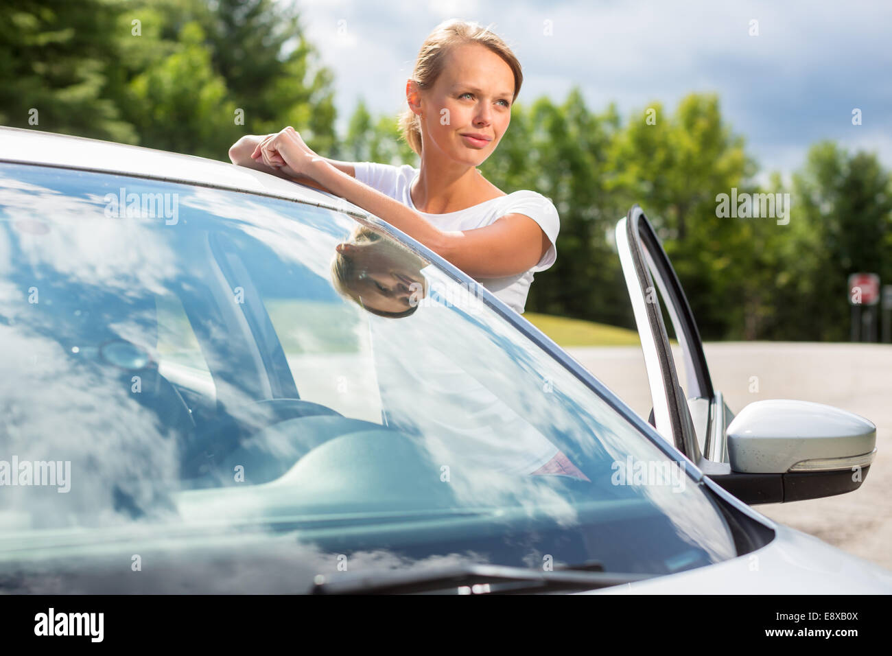 Young, attractive, happy woman standing by her car, being a proud owner ...