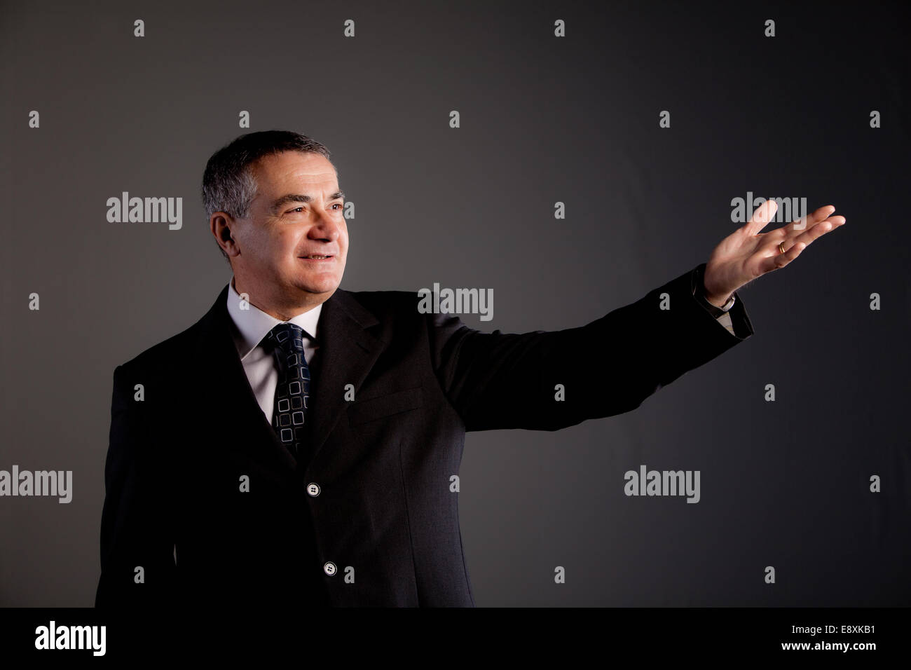 Senior executive raising a hand showing something Stock Photo - Alamy