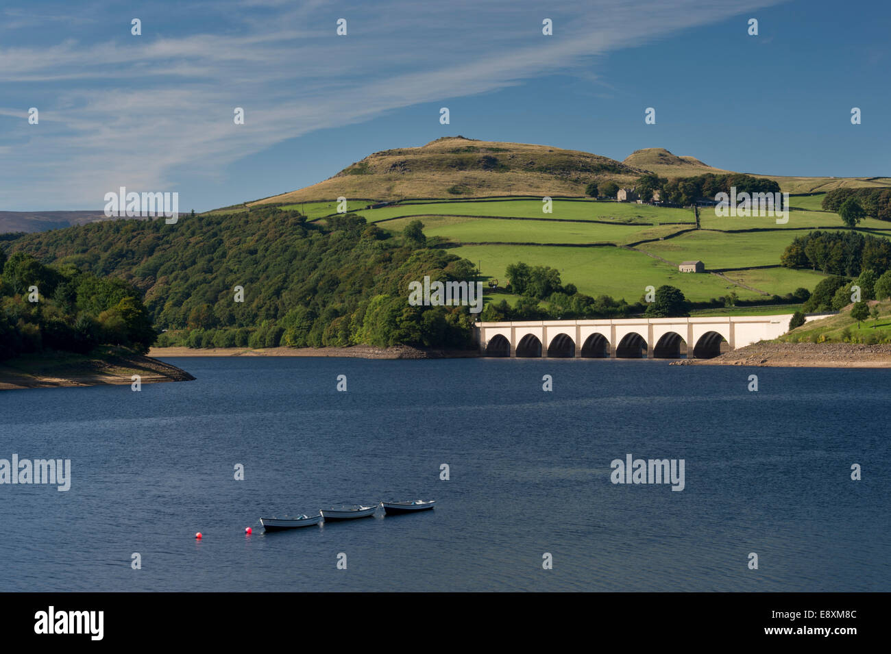 Blue summer sky over water of Ladybower Reservoir, boats moored, arches ...