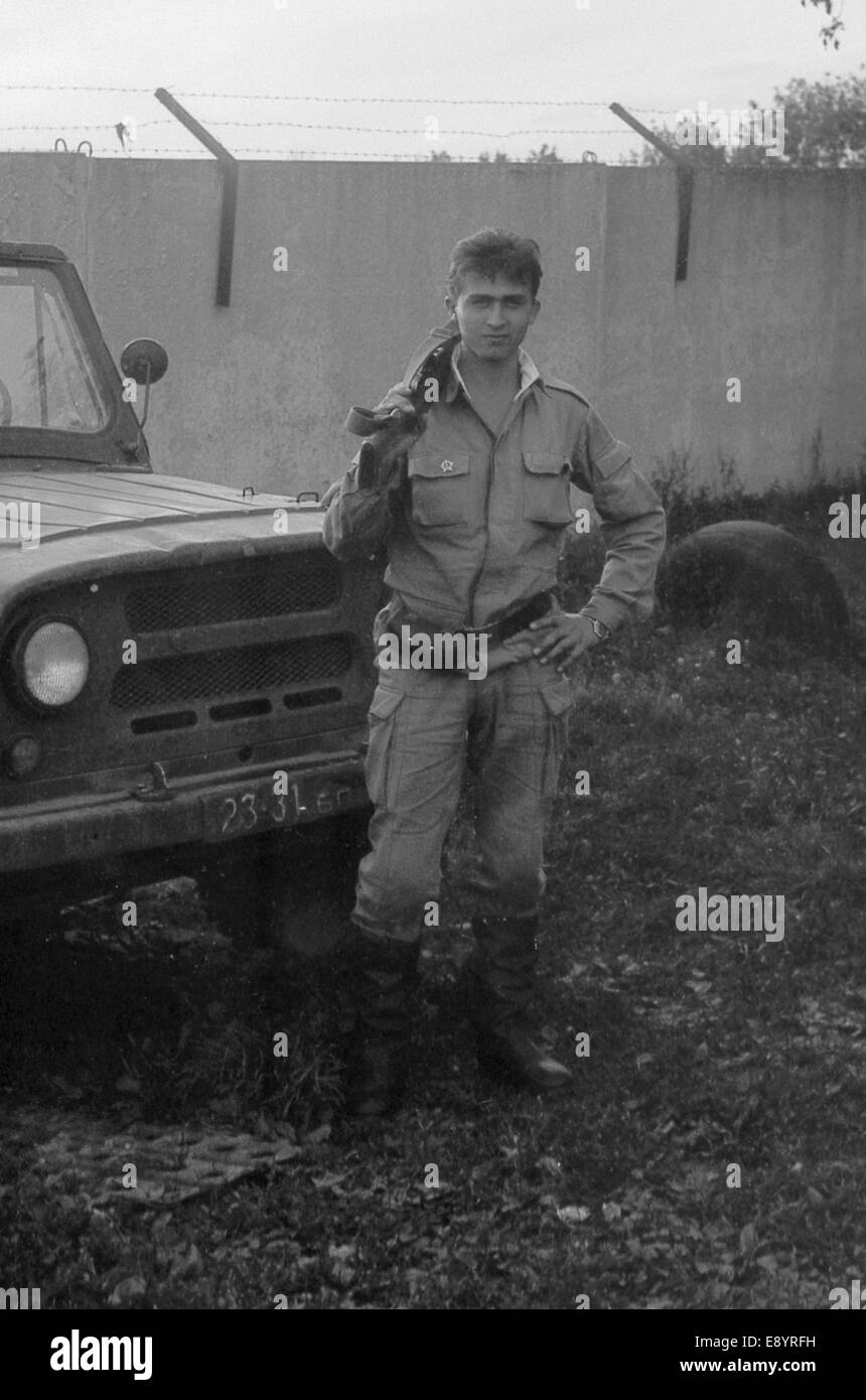 MOSCOW REGION, RUSSIA - CIRCA 1993: A soldier with a gun standing near army SUV UAZ-469. Film ...
