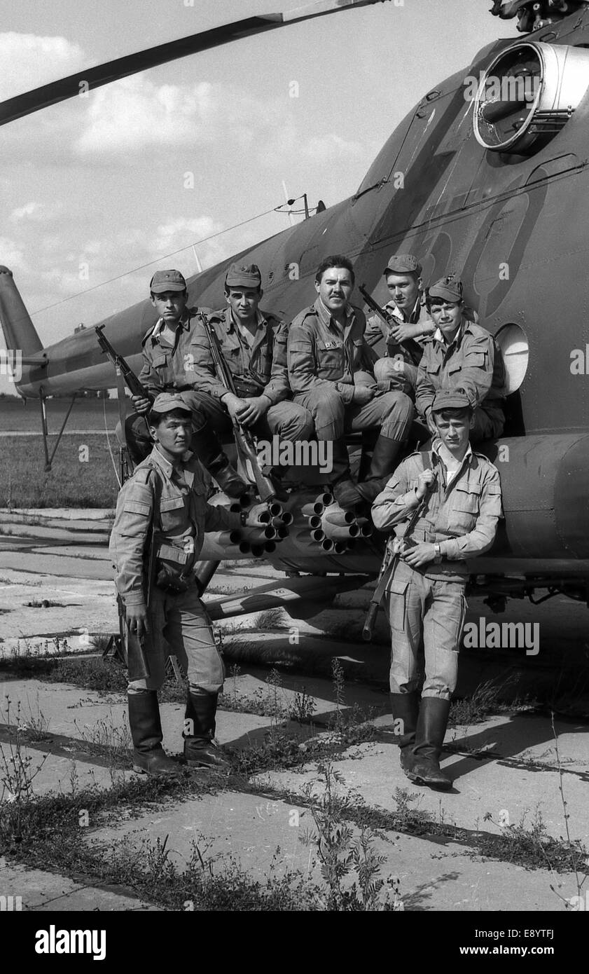 A squad of soldiers standing near a combat helicopter Mi-8. Film scan ...