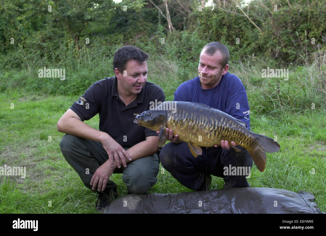 Men holding carp they've just caught on lake in Gloucestershire England ...