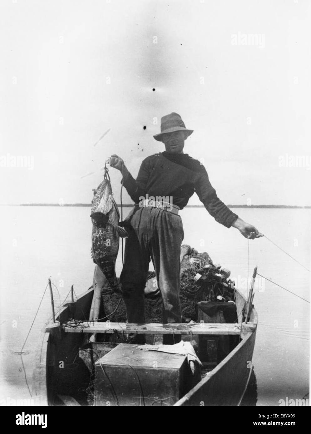 A fisherman stands in his boat proudly displaying a large catch ...