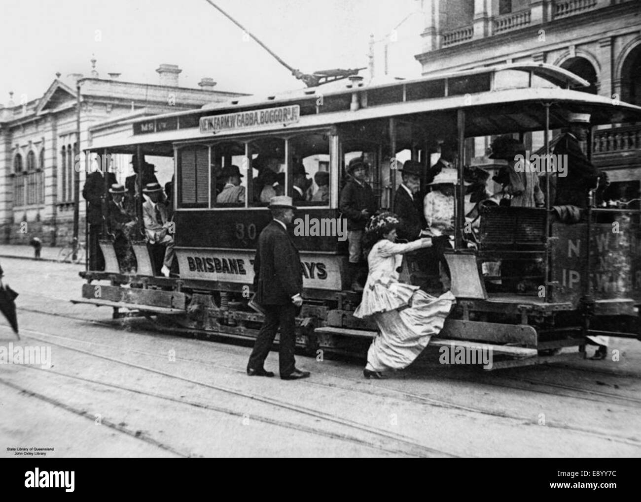 This photograph depicts a woman boarding a tram in Brisbane, likely ...