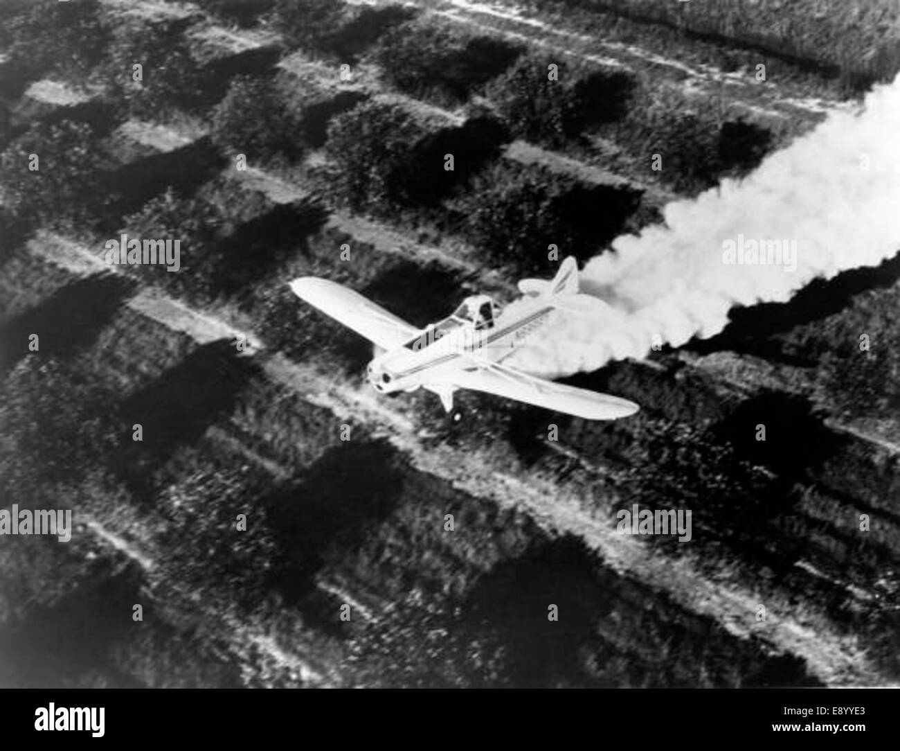 This photograph captures a crop dusting aircraft in action over a ...