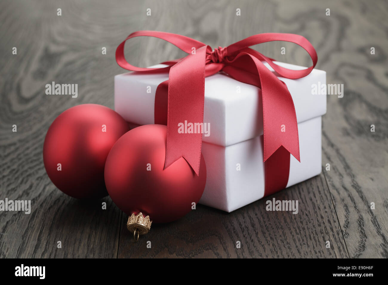 gift box with red ribbon bow and christmas balls, on oak table Stock ...