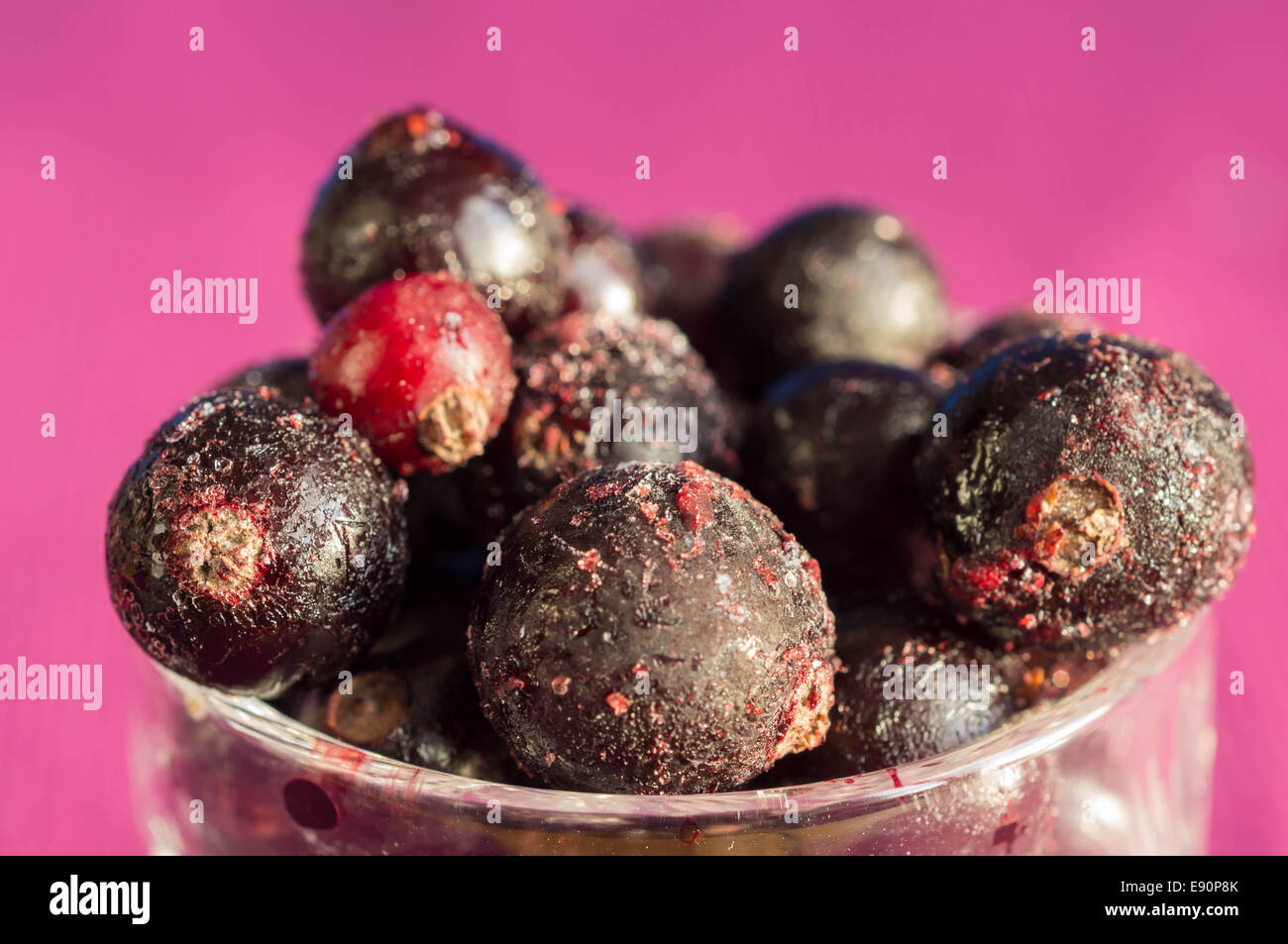 The frozen black currant in a glass on a crimson background Stock Photo ...