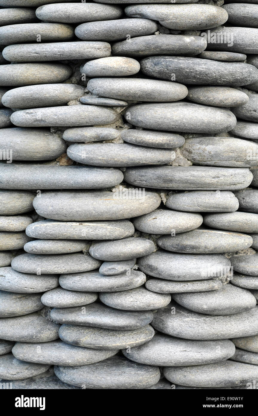Wall of flat pebbles bonded together with cement Stock Photo - Alamy