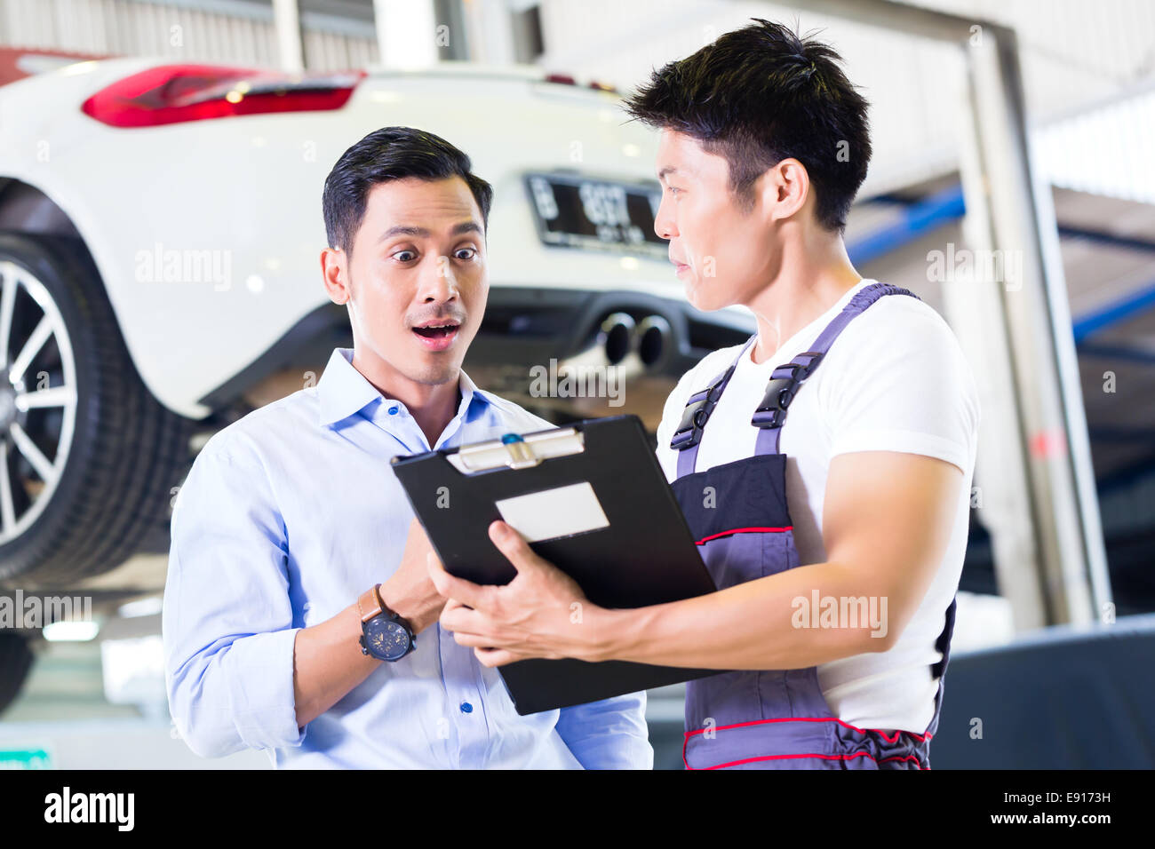 Asian Chinese car mechanic with customer going through the maintenance ...