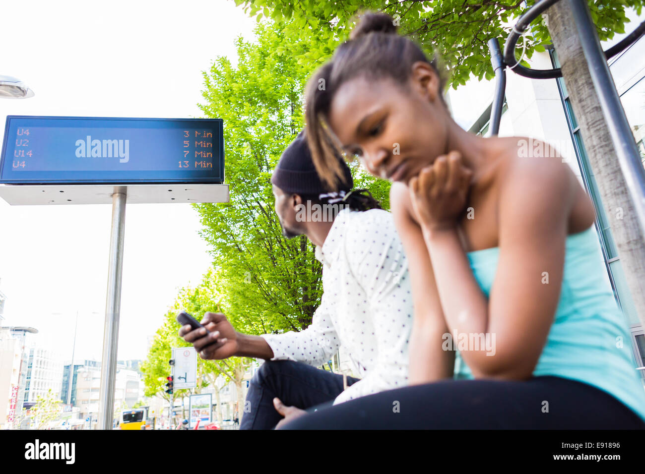 African man and girlfriend waiting at bus station Stock Photo - Alamy