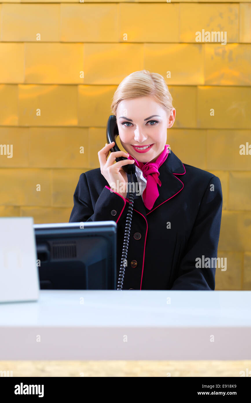 Hotel receptionist with phone on front desk Stock Photo - Alamy